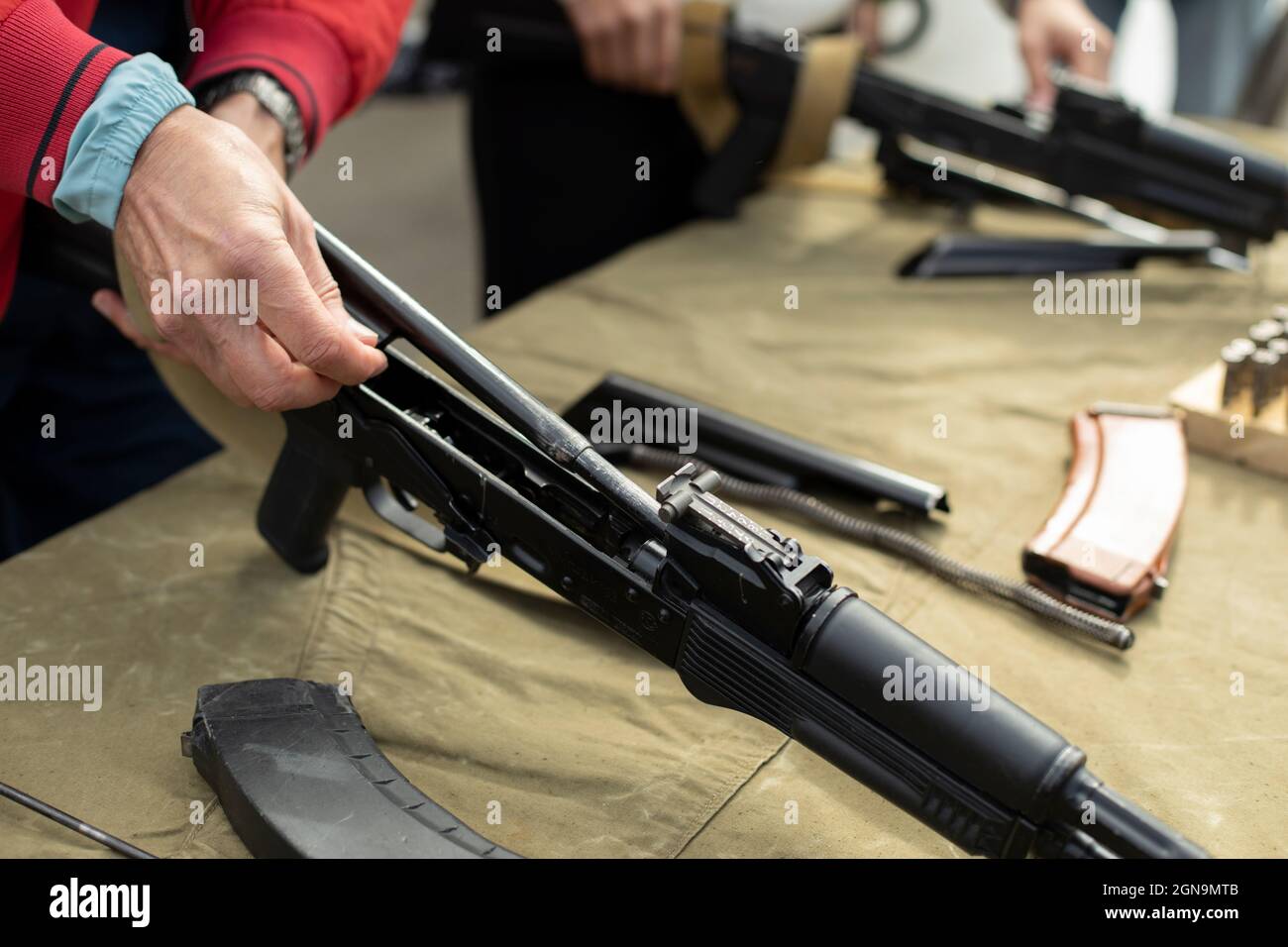 A man disassembles a firearm. A person undergoes military training ...