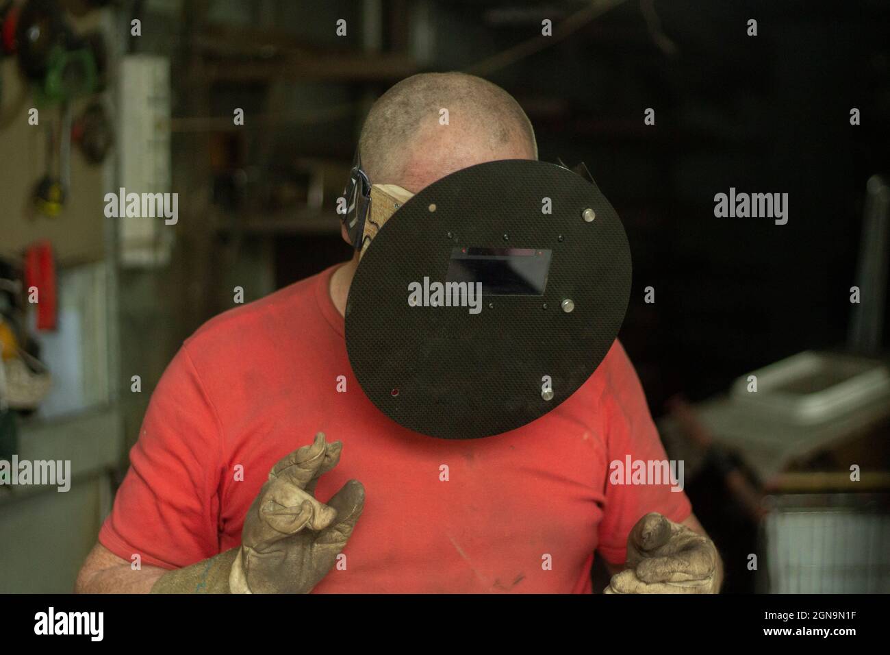 A masked welder works in a workshop. The man works with metal. The guy ...
