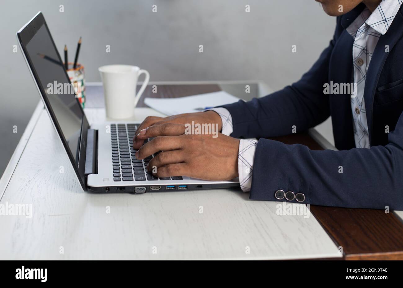 Closeup of an adult corporate employee working on his laptop on a desk ...