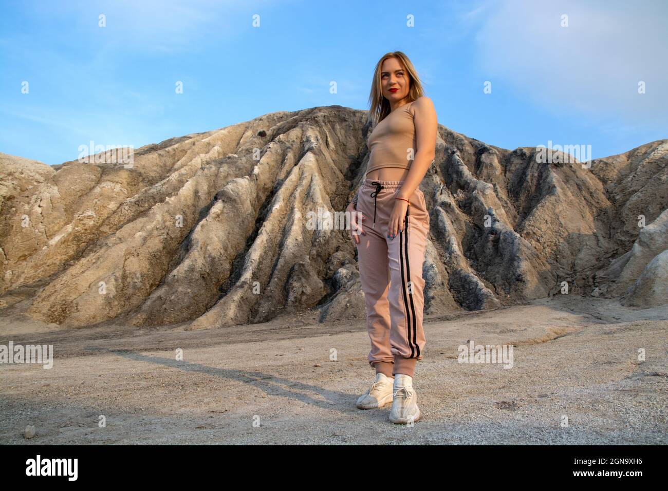 a young blonde girl in casual clothes in the mountains of red clay.ural mars. quarry for the ...