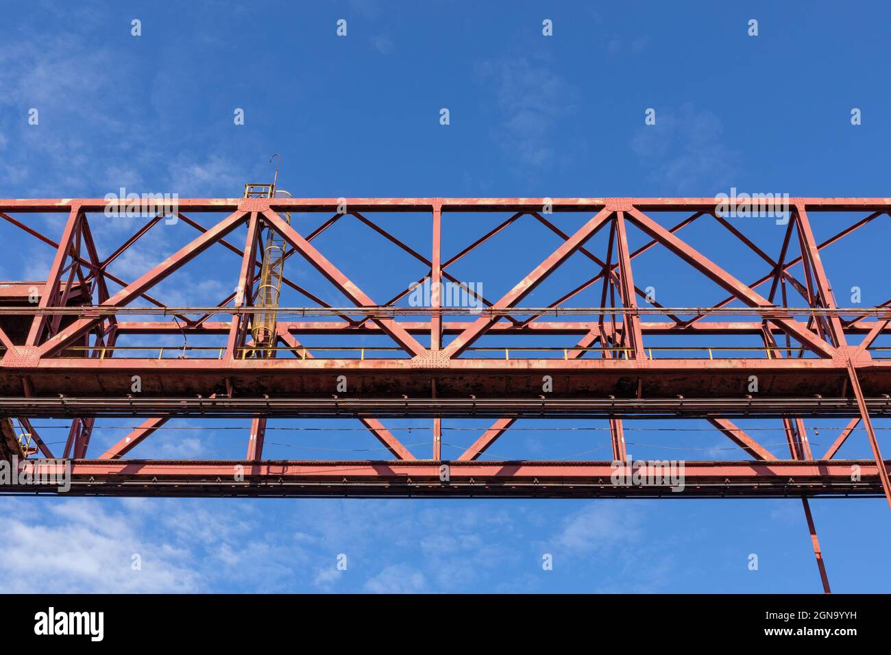 Overhead industrial structure painted red, isolated against a vivid ...