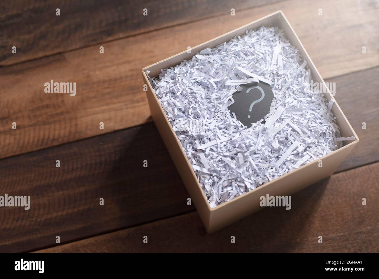 Question mark in a box with shredded paper on wooden table. Concept of ...
