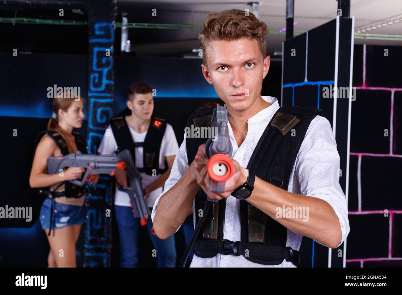 Portrait of excited guy with laser pistol playing laser tag in arena ...