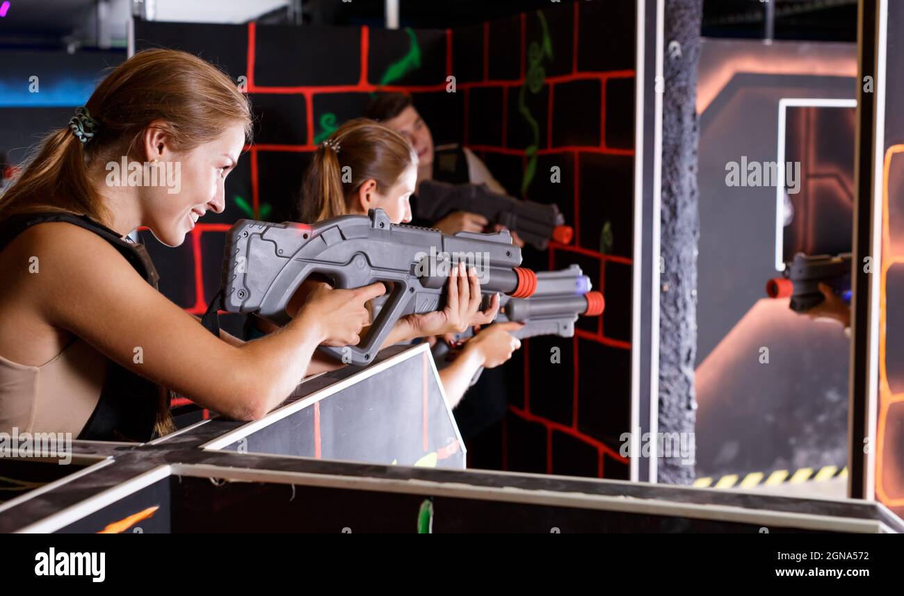 Smiling people in vests and with laser pistols playing emotionally ...