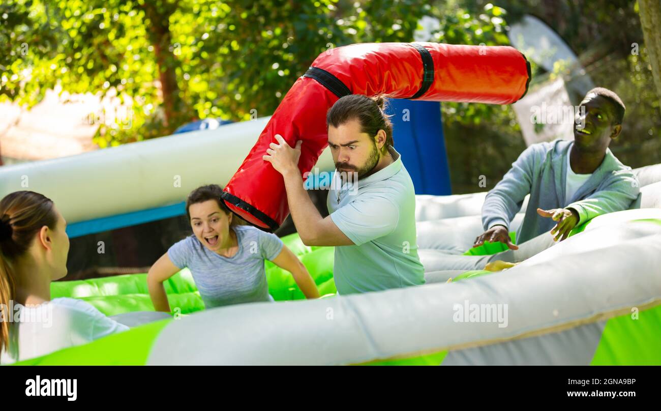 Funny friends playing on an inflatable trampoline in an amusement park ...