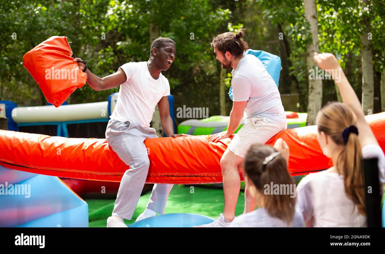 Men fighting by pillows on inflatable beam Stock Photo - Alamy