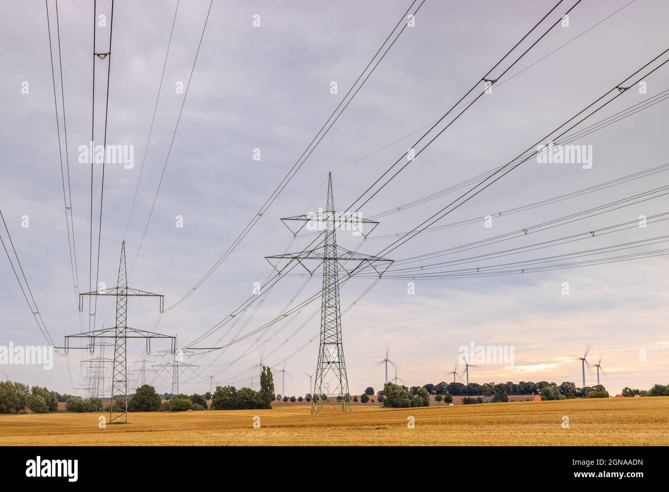 Shot of electricity cables and towers, and wind turbines over a rural ...
