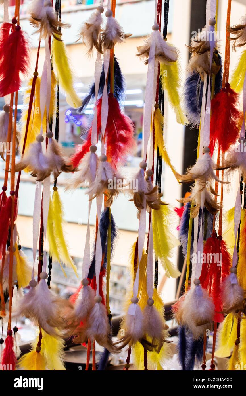 Closeup shot of long colourful feathers hanging in the outdoor market ...