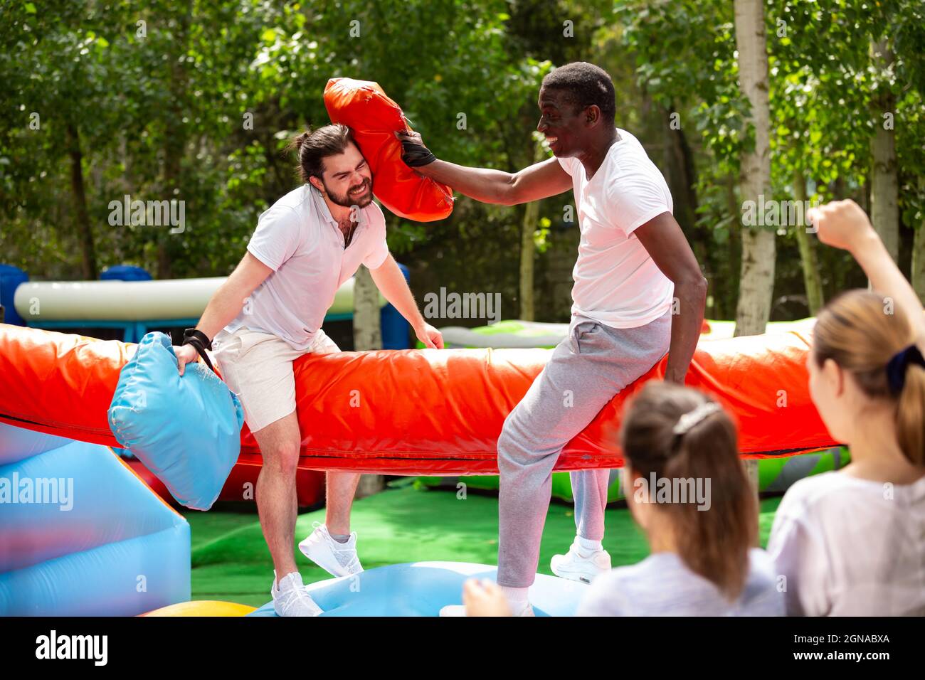 Men fighting by pillows on inflatable beam Stock Photo - Alamy