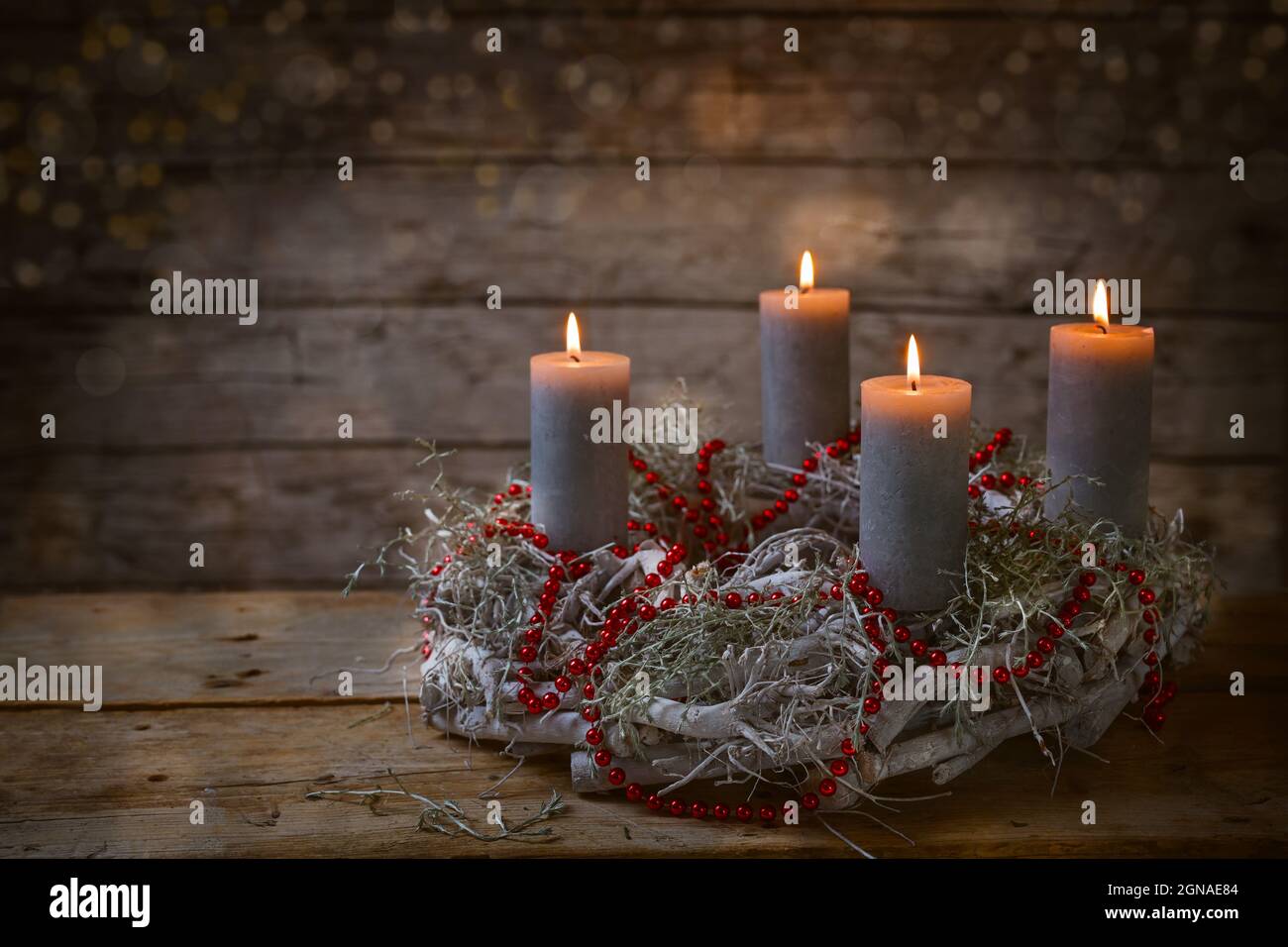 Advent wreath of branches with burning candles and red chain decoration ...