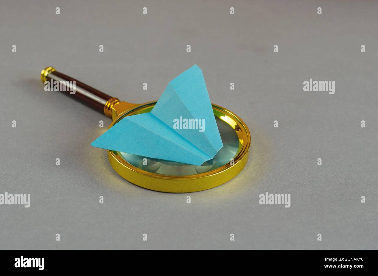 Paper airplane and magnifying glass on gray background. Small mo Stock ...