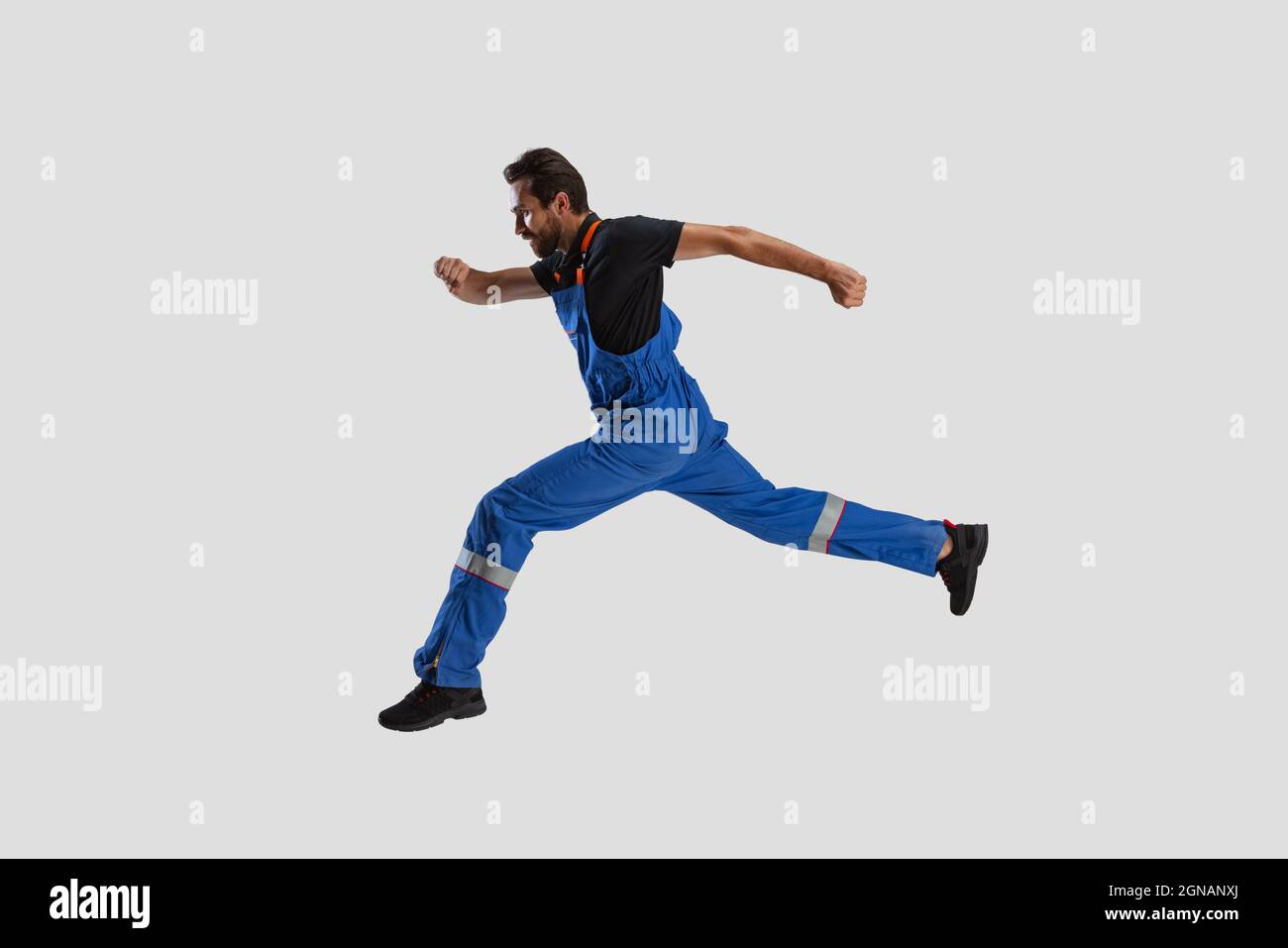 Portrait of young man, male auto mechanic in dungarees running isolated ...
