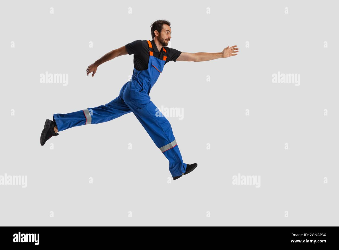Portrait of young man, male auto mechanic in dungarees running isolated ...