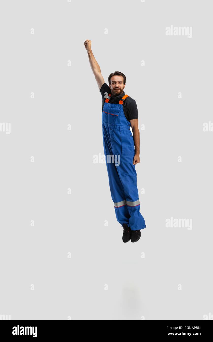 Comic portrait of young man, male auto mechanic in dungarees jumping ...