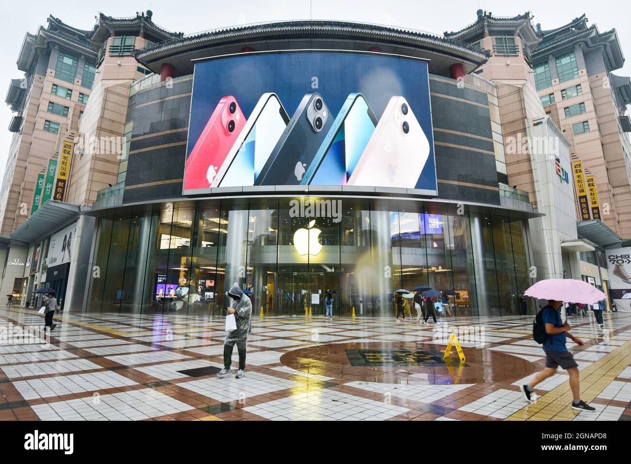 People walk past an apple store in Wangfujing with iPhone 13 series ...