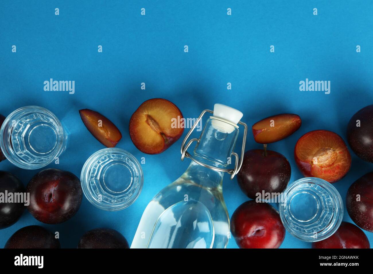 Bottle and shots of plum vodka and ingredients on blue background Stock ...