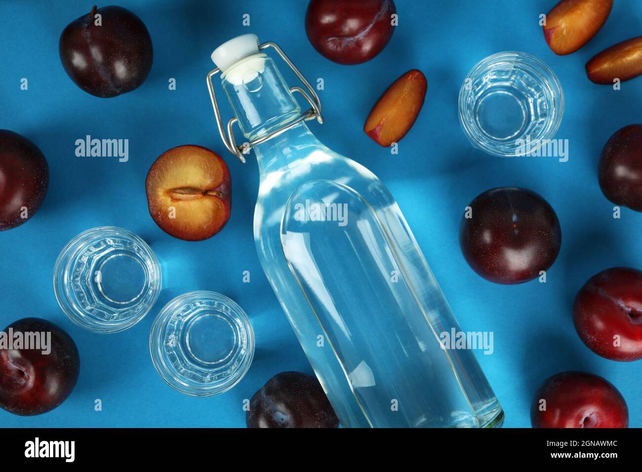 Bottle and shots of plum vodka and ingredients on blue background Stock ...