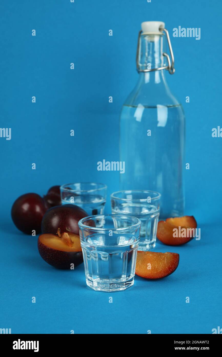 Bottle and shots of plum vodka and ingredients on blue background Stock ...