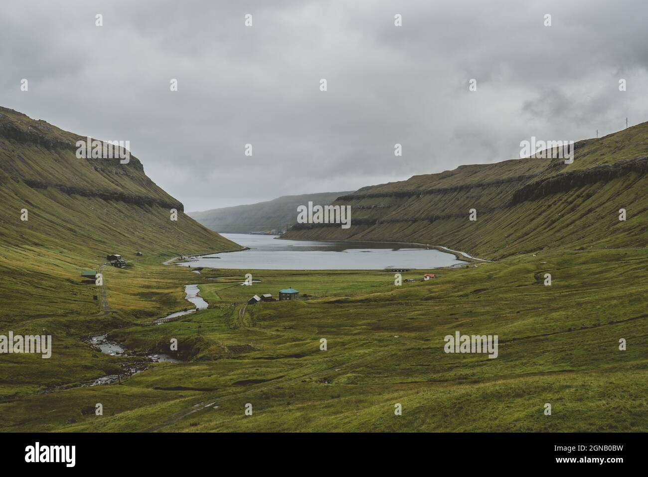 Green fields and mountains, fjord and nordic landscape, moody grey sky ...