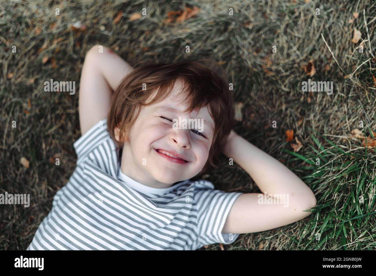 Kid lying on his back in the grass in park. Boy chilling on green lawn ...