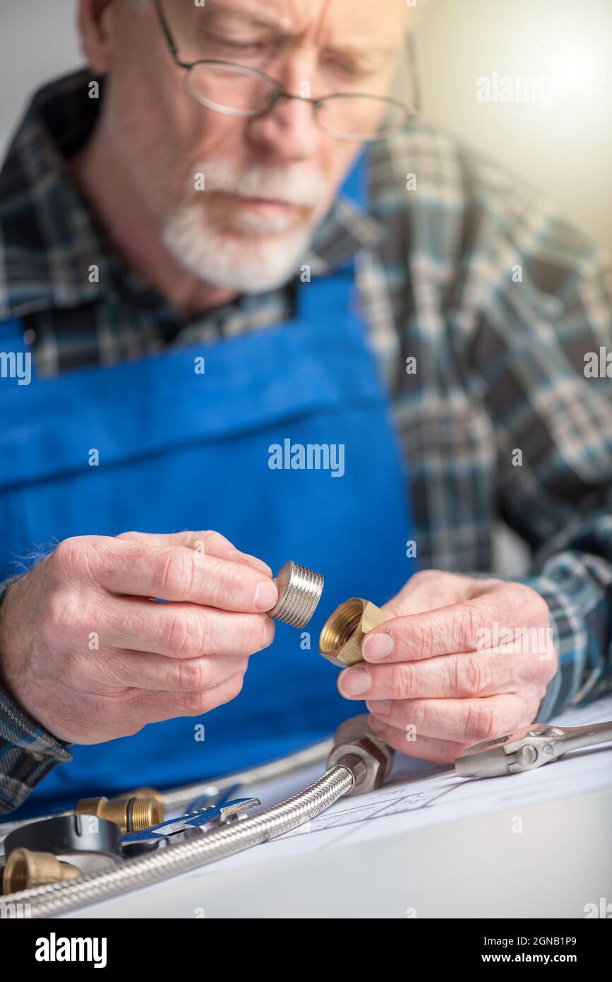 Senior plumber using plumbing fittings, light effect Stock Photo - Alamy