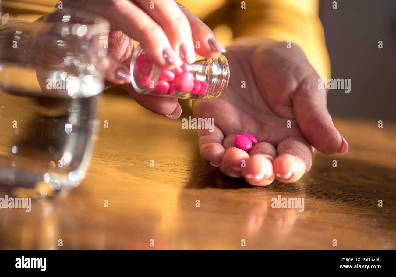 Close up of female hands taking medication, hard light Stock Photo - Alamy