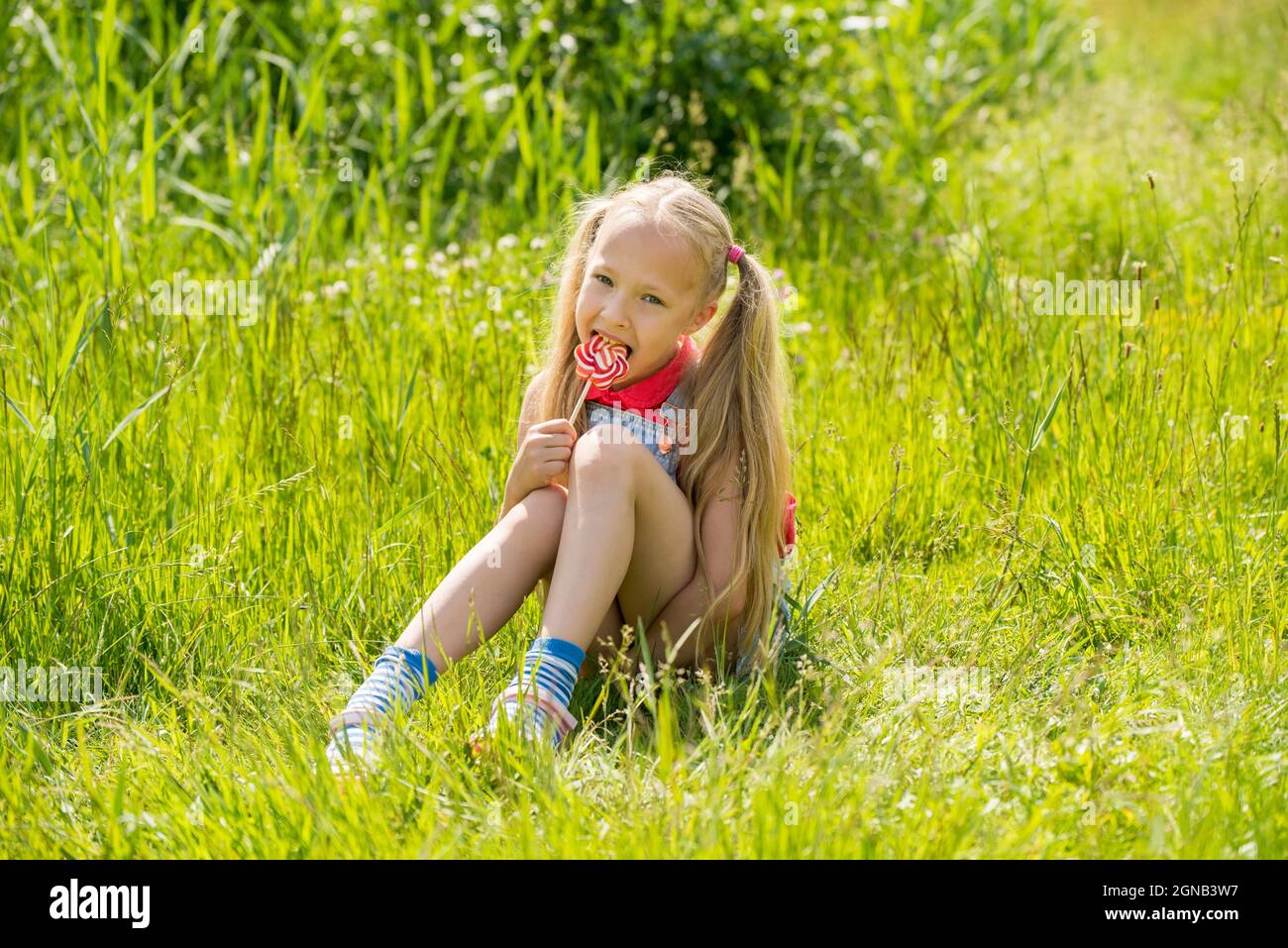 Blonde little girl with long hair and candy on a stick Stock Photo - Alamy