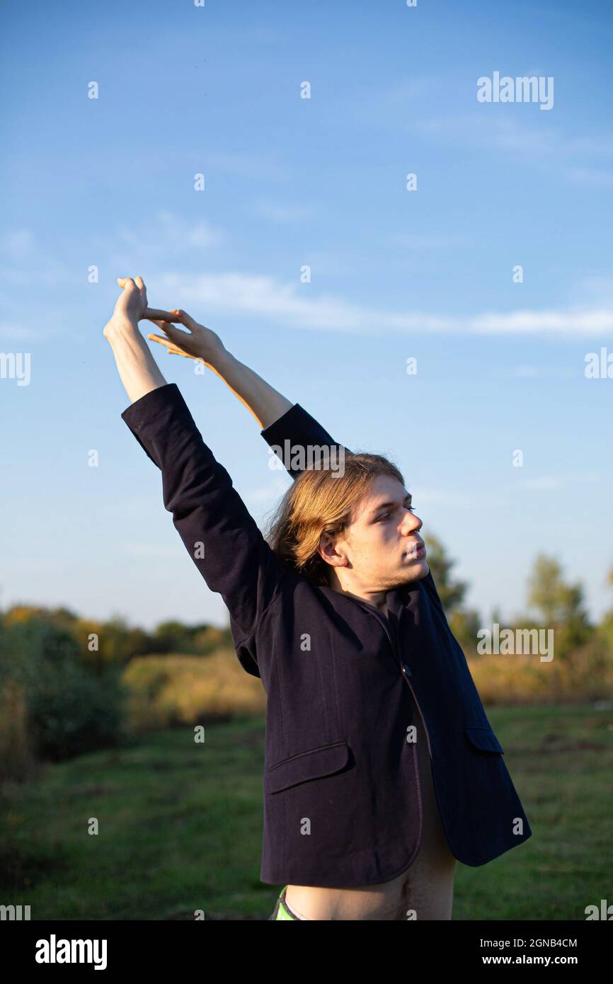 Young european white man with long hair with sky behind sunset light ...