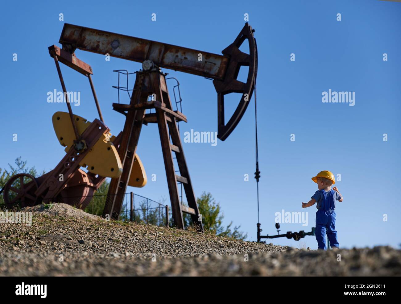 Back view of male child learning business development at oil station ...