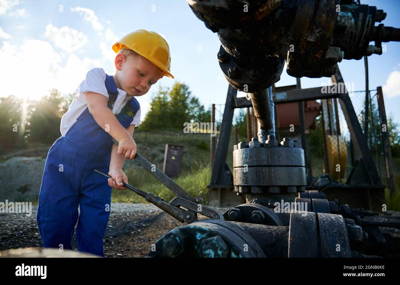 Caucasian blonde boy with instrument fixing drilling rig during time ...