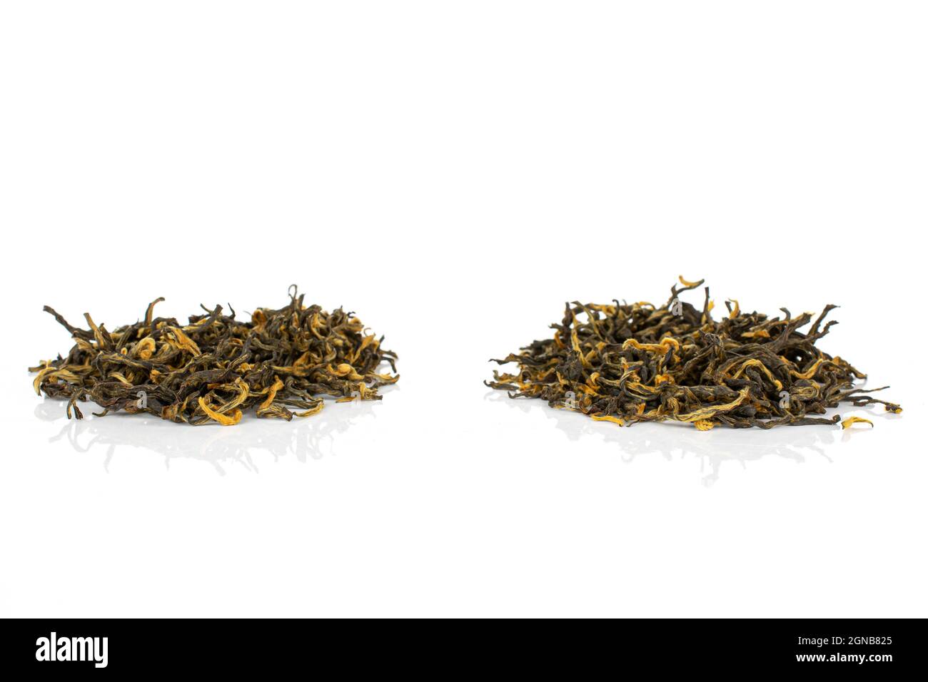 Dry black tea leaves in two groups in row isolated on white background ...