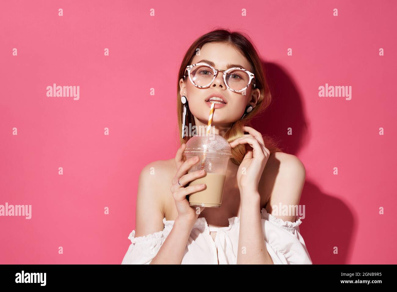 pretty woman a glass with a drink pink background Stock Photo - Alamy