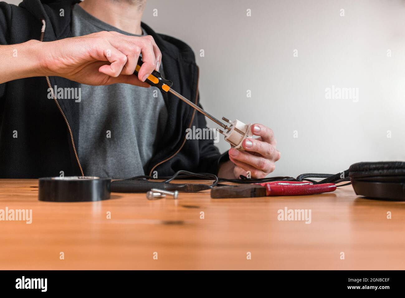 Man at home with screwdriver opening an electrical adapter Stock Photo ...
