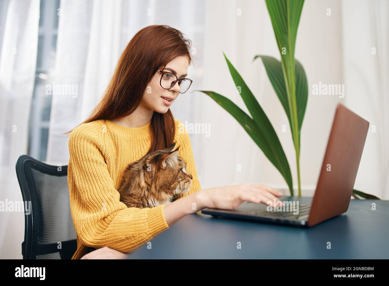 woman in a yellow sweater in front of a laptop at home work freelance ...