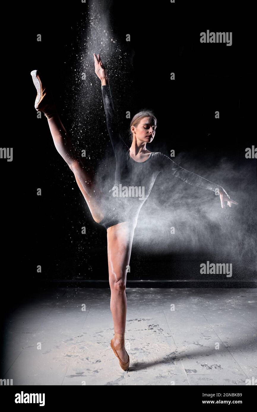 Dancer posing dancing gracefully in studio with cloud of dust, flour ...