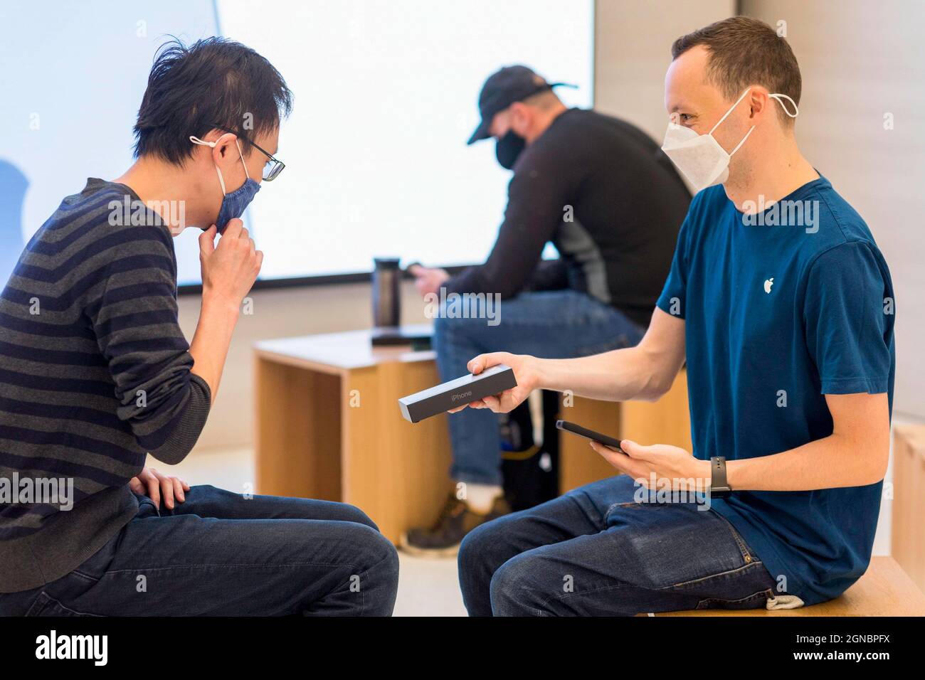 An Apple staff seen handing a customer his copy of the iPhone 13. Apple ...