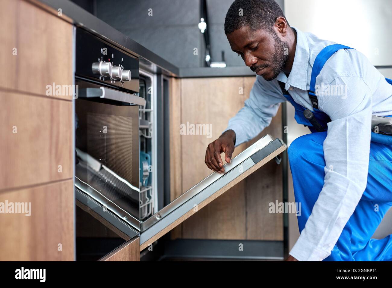 Serious african man or service worker in special clothing installs ...