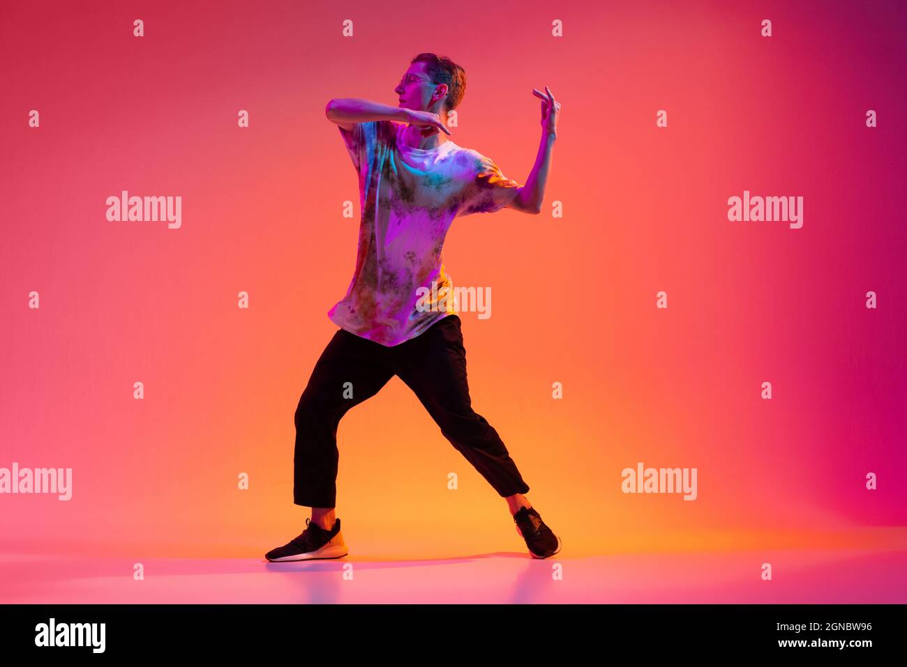 Handsome sportive boy dancing hip-hop in stylish clothes on colorful ...