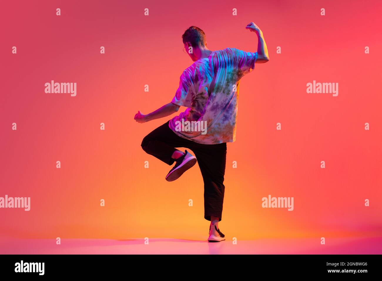 Back view of young stylish man dancing hip-hop isolated over colorful ...