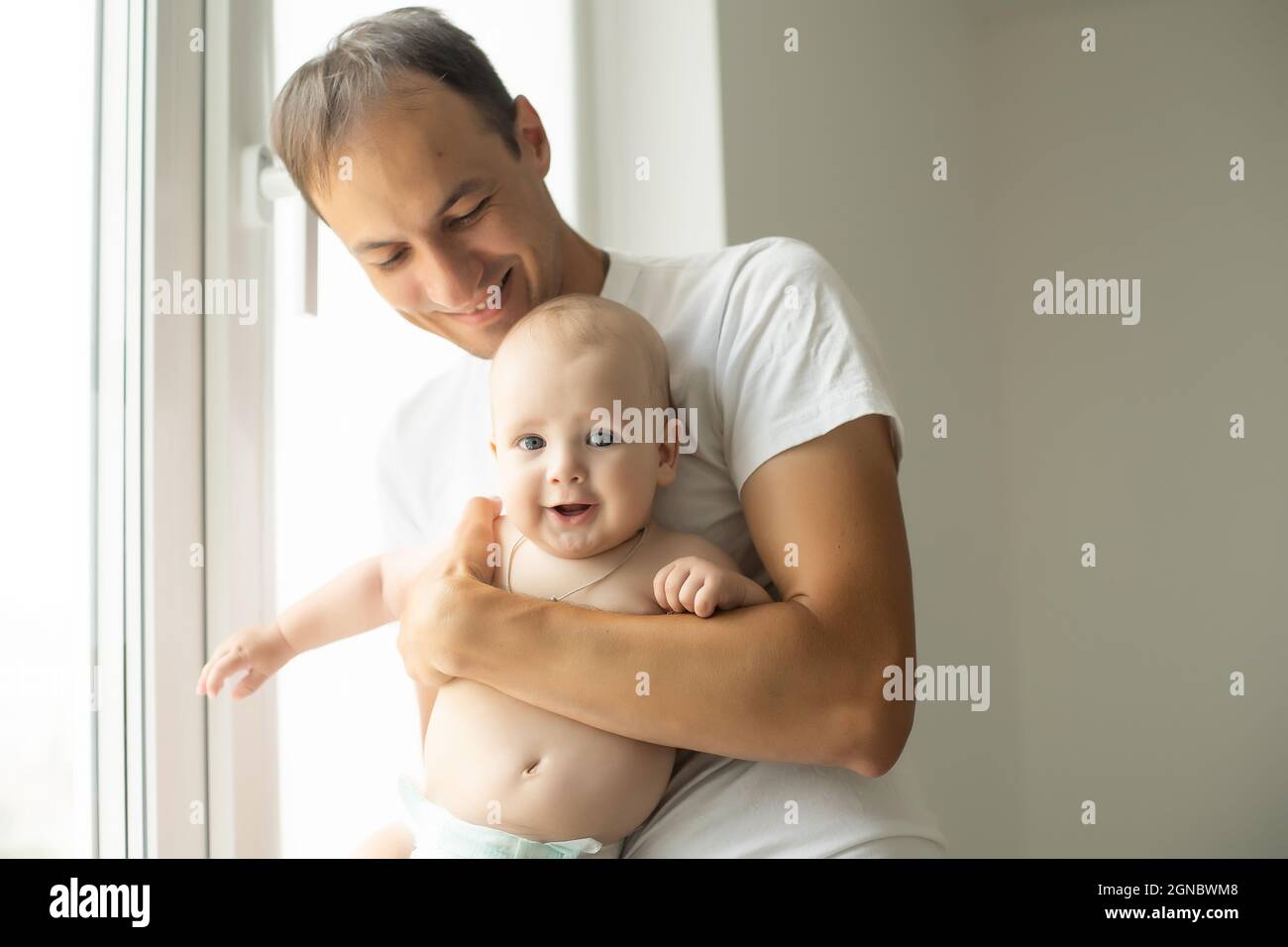 Father Hugging Newborn Baby in white bedroom Stock Photo - Alamy