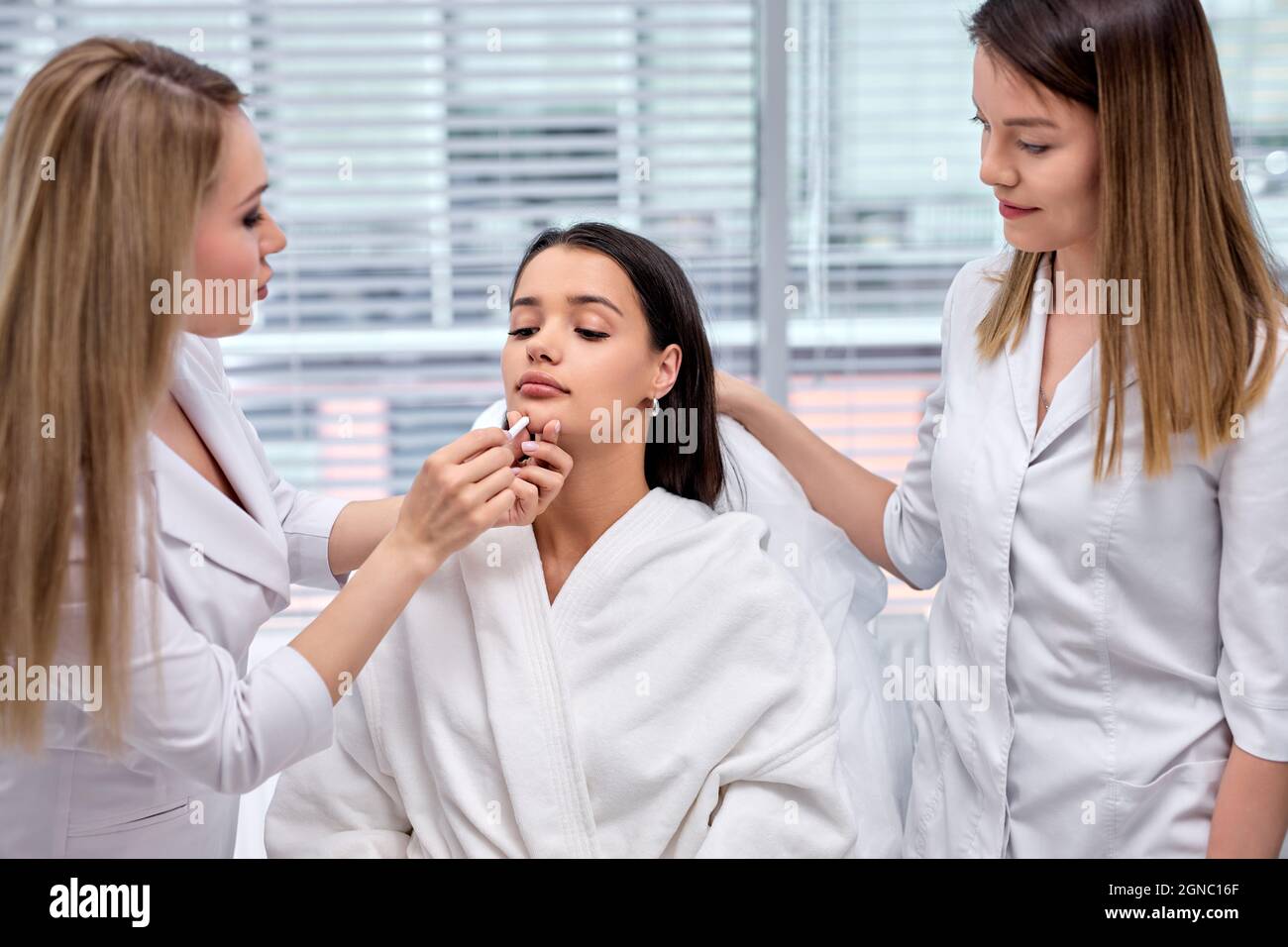 professional caucasian plastic surgeon and assistant drawing contours ...