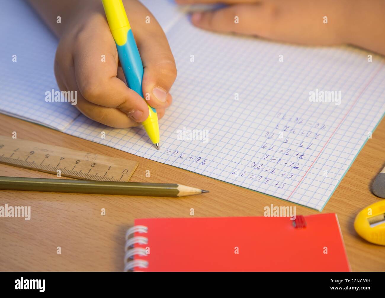 Pupil's hand close-up solves math examples with a ballpoint pen. A ...