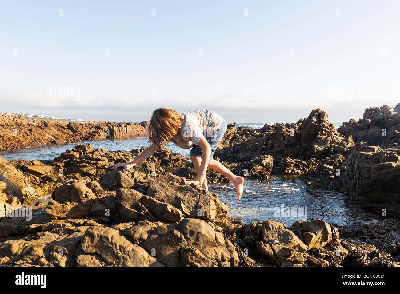 A young boy exploring the rock pools on a jagged rocky Atlantic Ocean ...