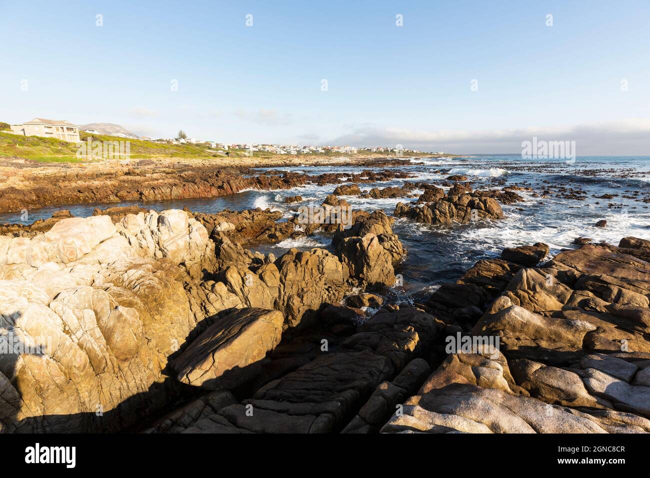 Jagged ridges of rock reaching out into the sea at De Kelders, South ...