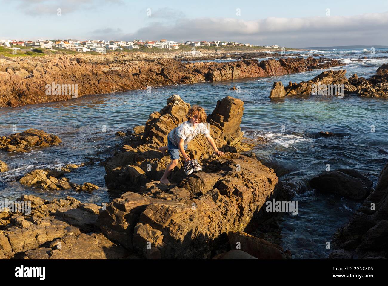 A young boy exploring the rock pools on a jagged rocky Atlantic Ocean ...