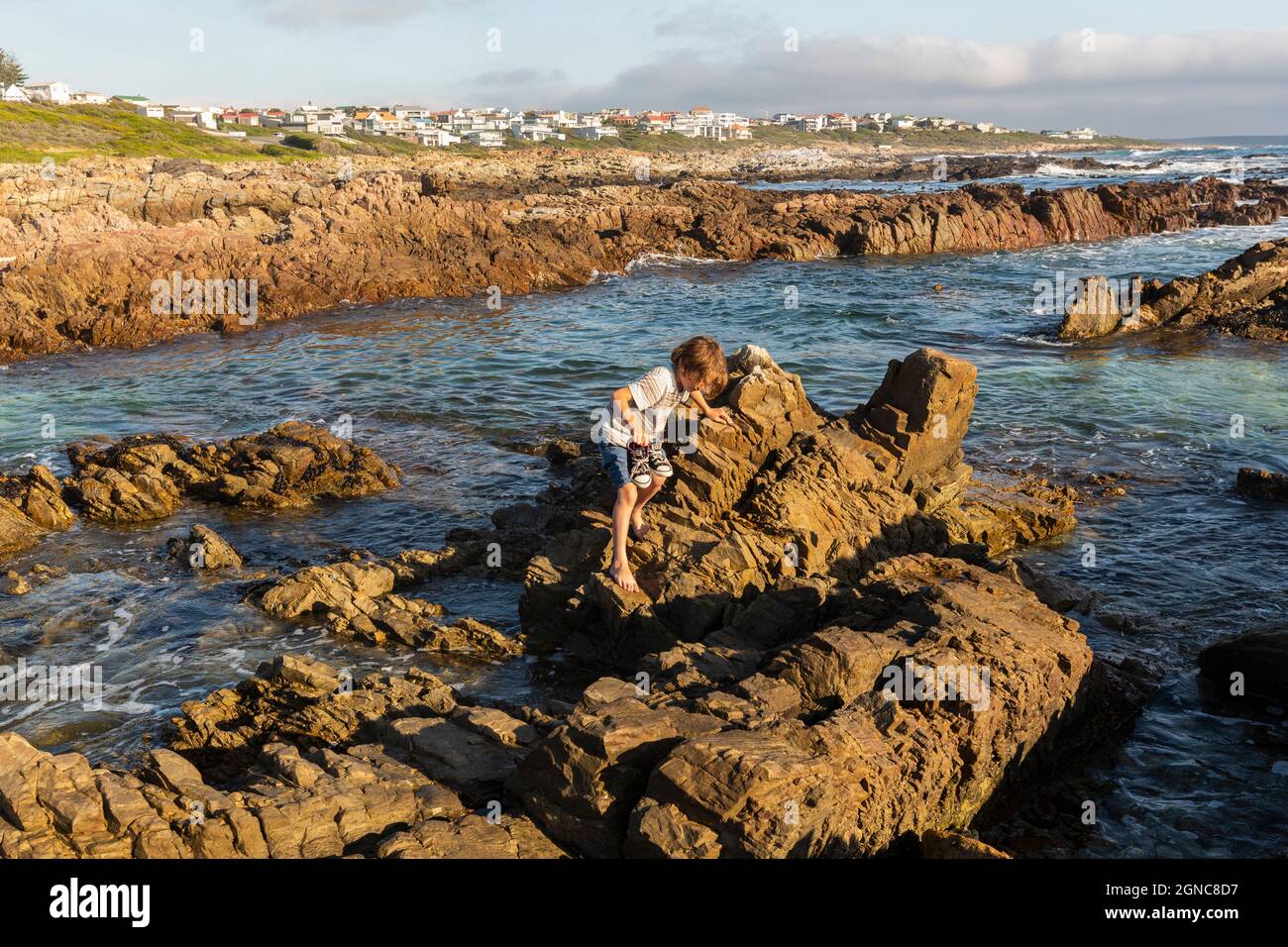 A young boy exploring the rock pools on a jagged rocky Atlantic Ocean ...