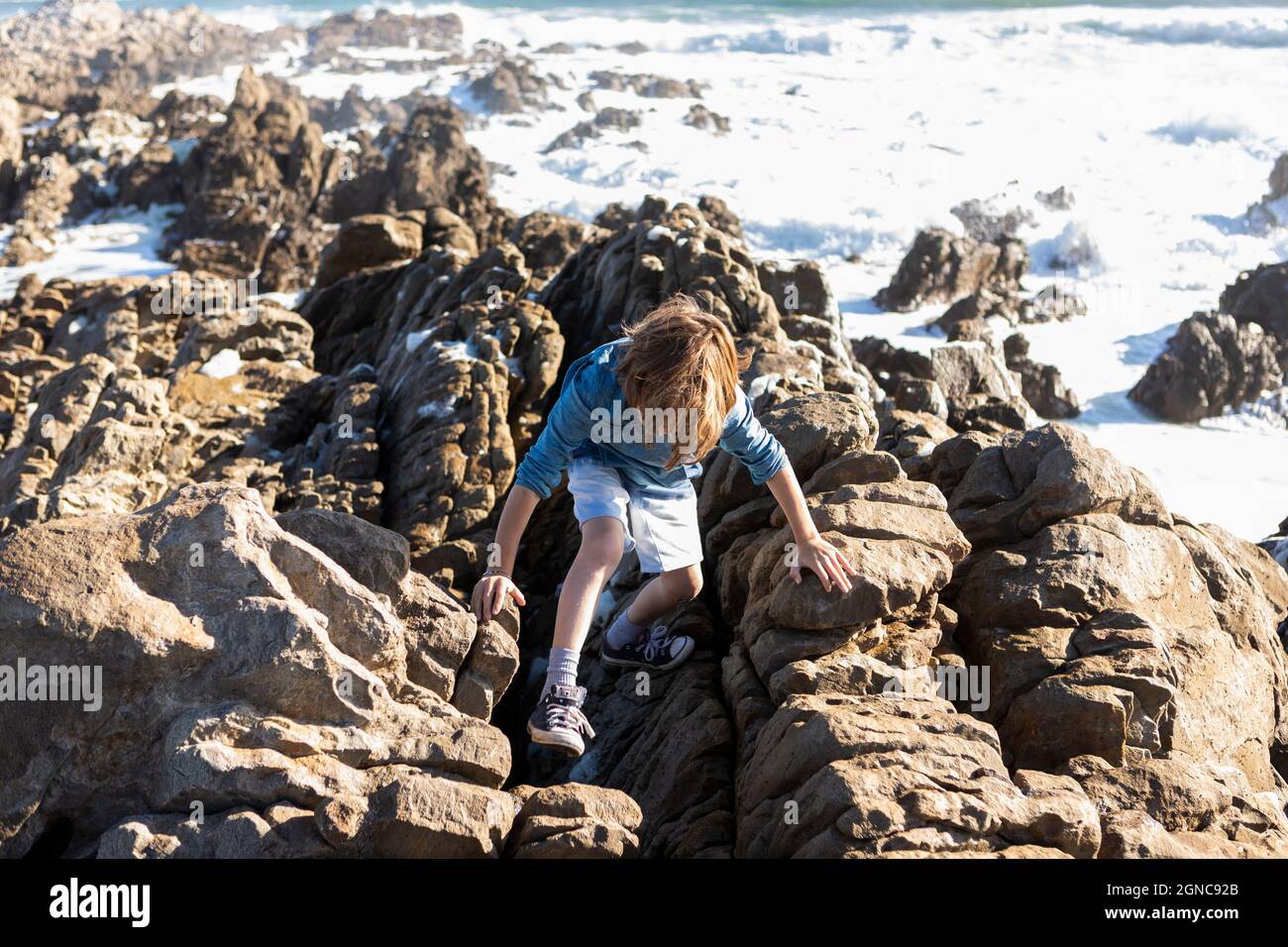 Boy exploring the jagged rocks and rock pools on the Atlantic Ocean ...