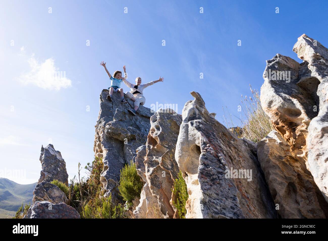 Two children climbing on top of large sandstone rock formations on a ...