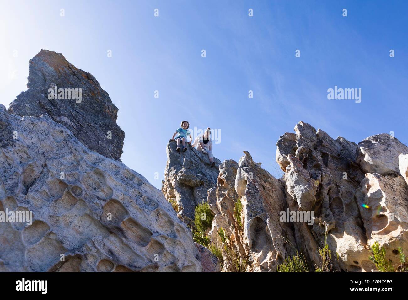 Two children climbing on top of large sandstone rock formations on a ...