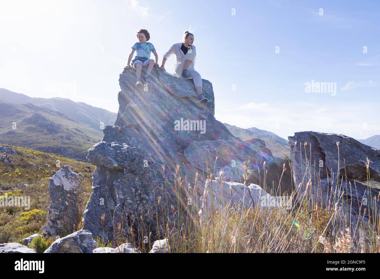 Two children climbing on top of large sandstone rock formations on a ...
